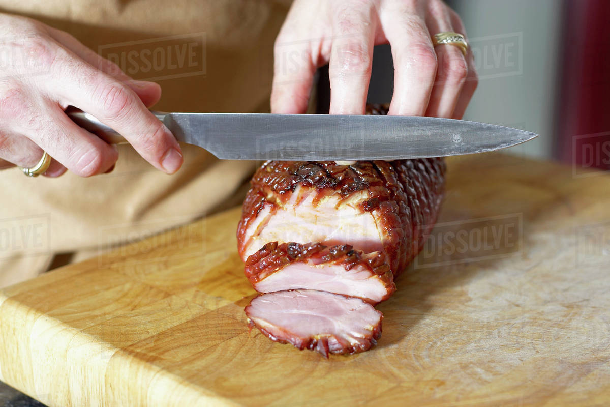 Oven Roasted Ham Being Sliced On Cutting Board With Large Knife ...
