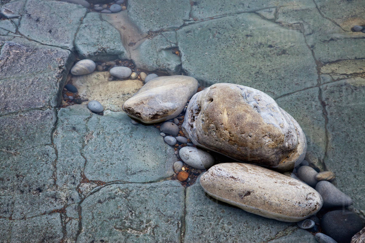 Rocks Sitting In The Crack Of A Rock Slab Covered With Clear Water ...