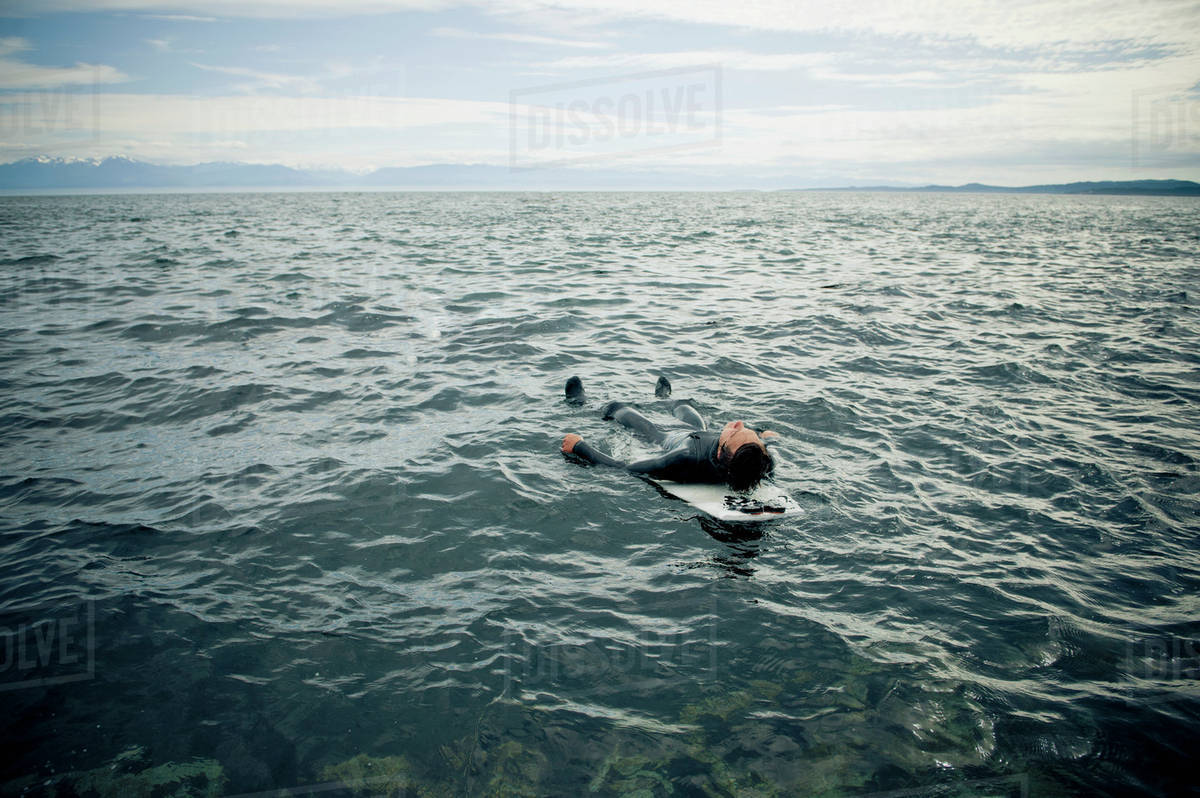 A Surfer Lays On His Back On His Surfboard In The Water; Victoria ...