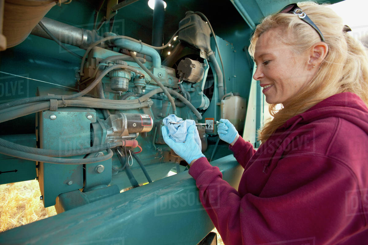 A Woman Working On Heavy Equipment On A Farm; Three Hills, Alberta ...
