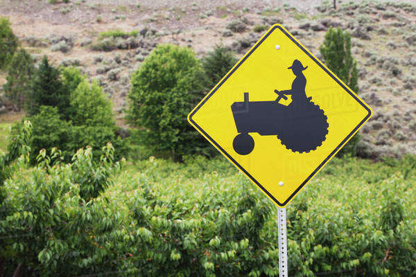 Farmer and tractor road sign with shrubs and gravel hillside in the ...