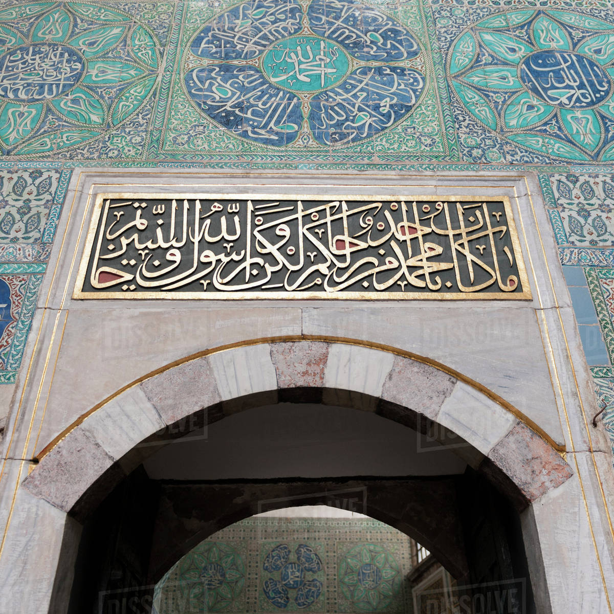 Ornate design in colourful tile on a wall above an arched doorway in ...