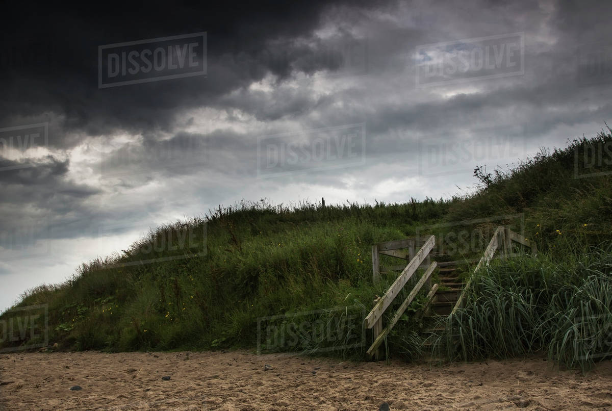 Wooden steps leading to the beach under dark storm clouds;Druridge bay ...