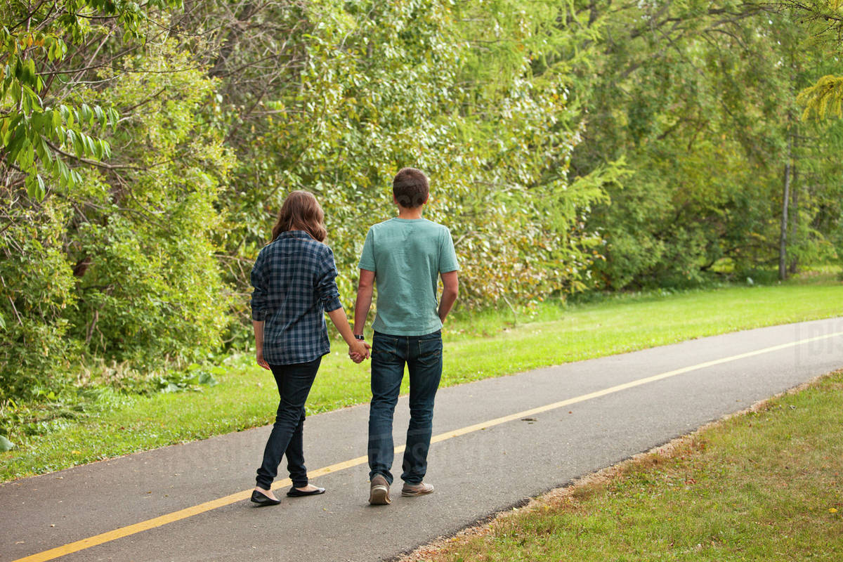 Young Couple Walking Down A Park Path; Edmonton, Alberta, Canada ...