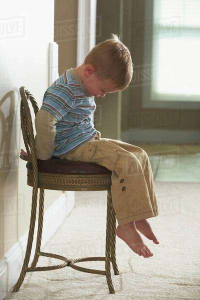 A Boy Sitting On A Chair Looking Sad - Royalty-free Stock Photo | Dissolve