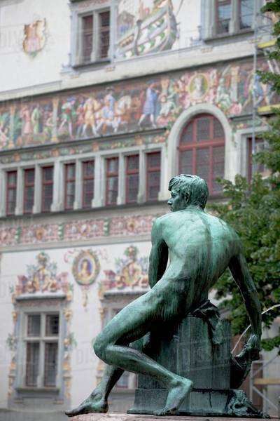 Bronze Male Statue With Colorfully Painted Buildings In The Background ...