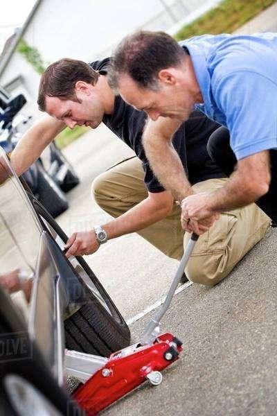 Two Men Fixing A Flat Tire - Royalty-free Stock Photo | Dissolve