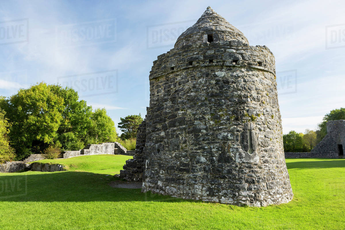 Round stone castle struture in grassy field with blue sky and clouds ...