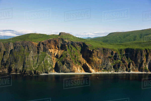 Aerial view of rocky cliffs and green hills along the shore of Popof ...