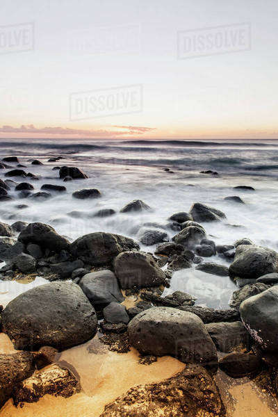 Water washing over rocks along the shore at sunset; Wainiha, Kauai ...
