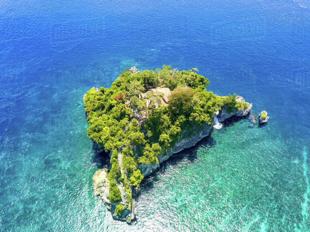Indonesia. Emerald ocean water. A small rocky island, overgrown with ...