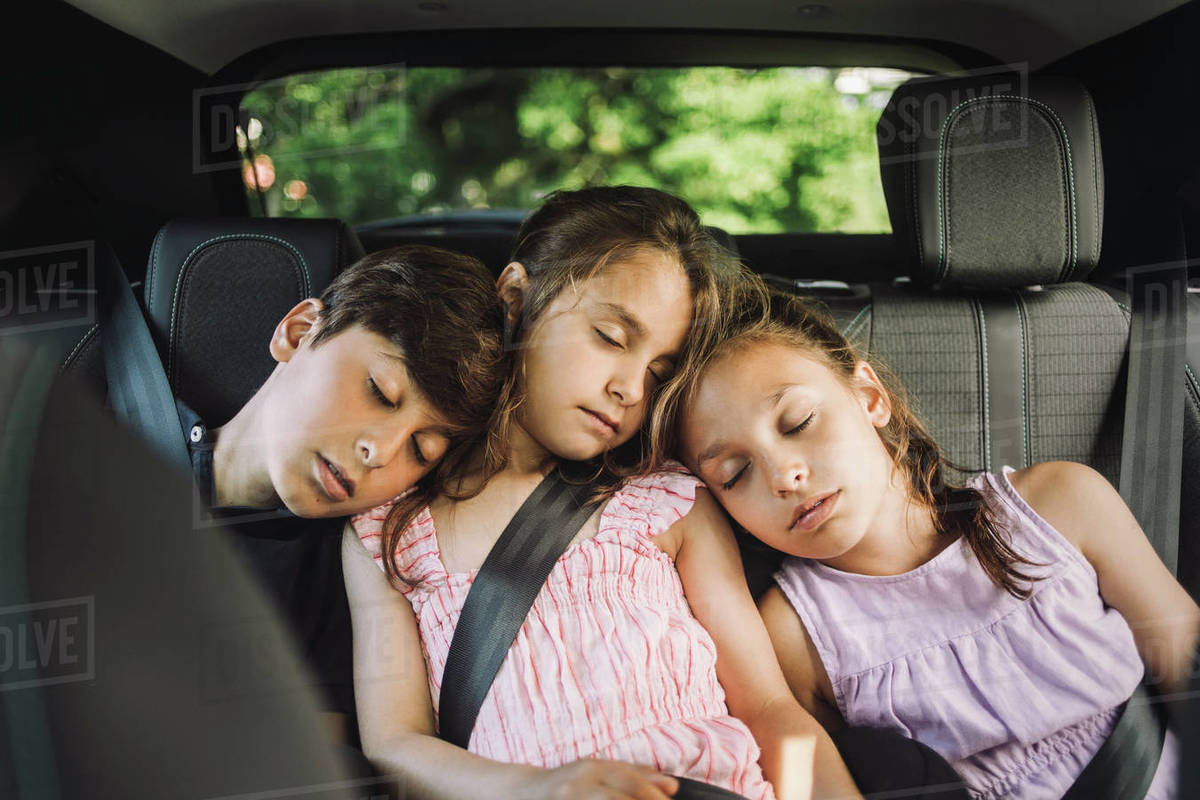 Tired siblings sleeping on back seat while traveling in car - Royalty ...