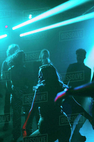 Rear view of young woman dancing near friends on dance floor at ...