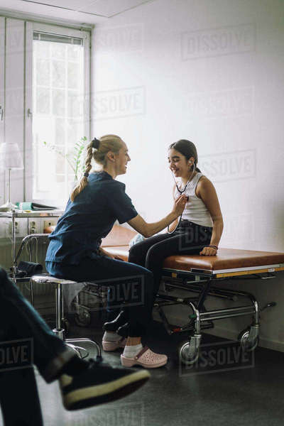 Female nurse examining girl sitting on bed in clinic - Stock Photo ...