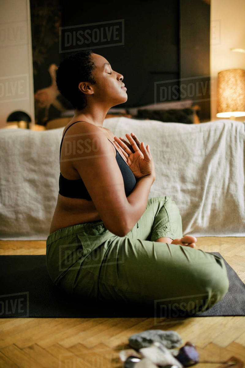 Side view of young woman meditating in bedroom at home - Royalty-free ...