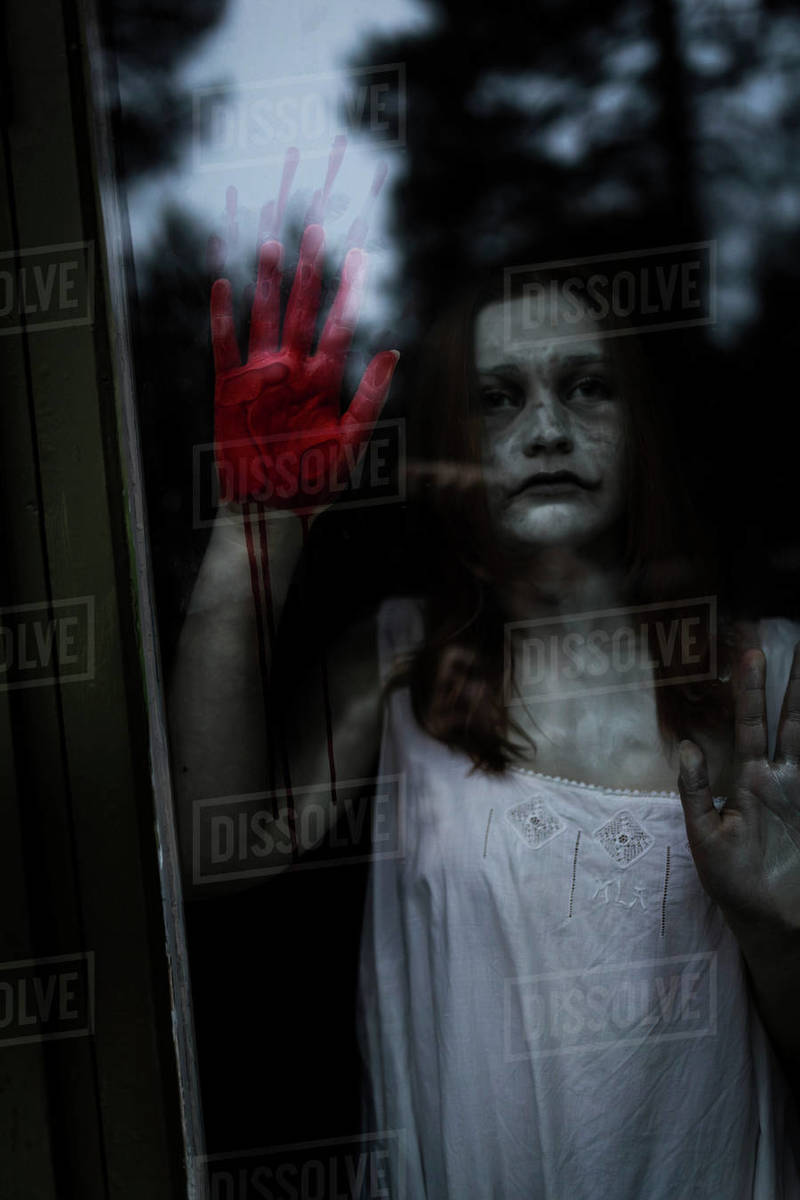 Female ghost with blood on hand seen through window of haunted cabin ...