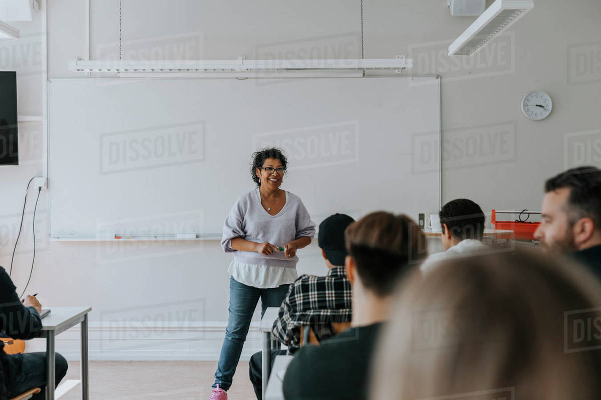 Smiling teacher teaching in classroom - Stock Photo - Dissolve