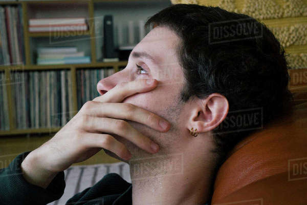 Side view of sad man crying with hand covering mouth at home - Royalty ...