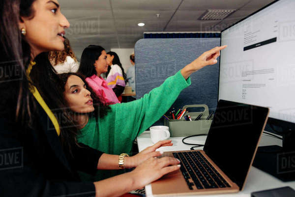 Businesswoman pointing at monitor screen with colleague working on ...