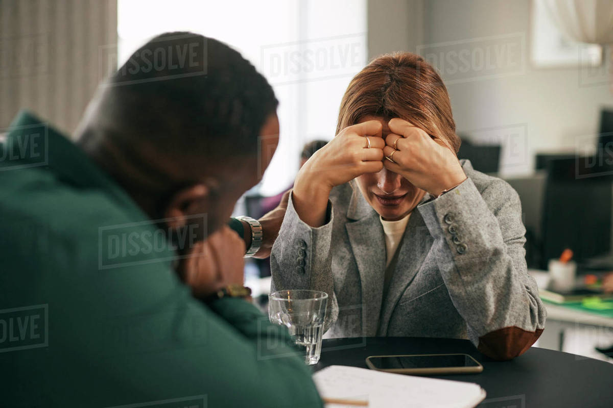 Male business professional consoling crying female colleague in office ...