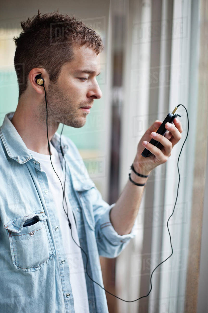 Side view of young man listening music through cell phone - Royalty ...