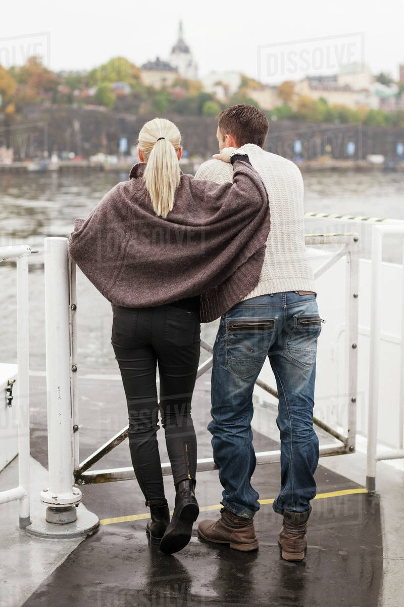 Rear view of young couple leaning on railing outdoors - Royalty-free ...