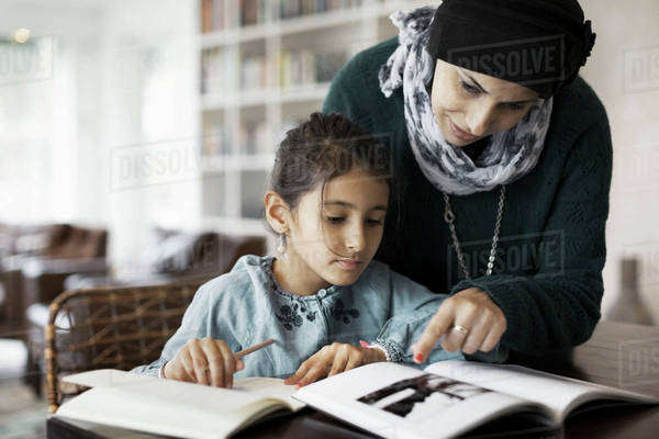 Mother assisting girl in doing homework at table - Royalty-free Stock ...