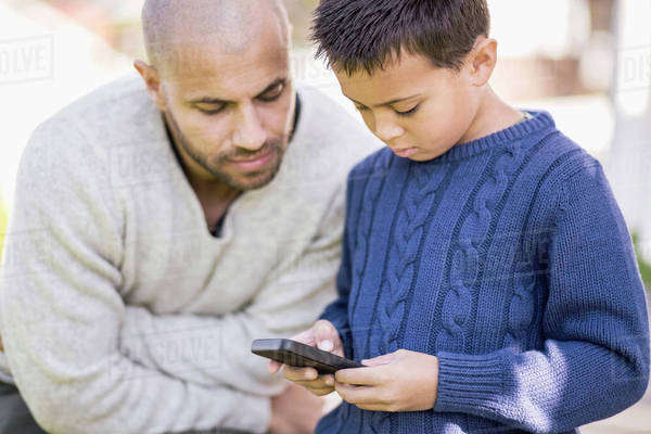 Father and son using mobile phone together - Royalty-free Stock Photo ...