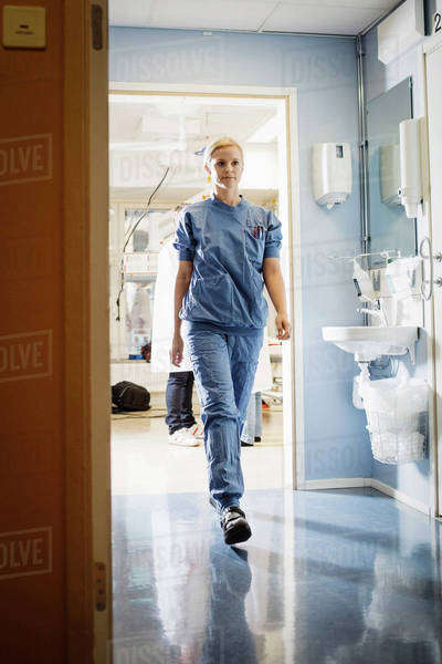 Full length of young female nurse walking in hospital corridor - Stock ...