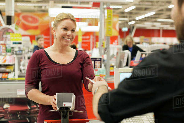 Smiling mid adult woman paying at grocery store counter - Stock Photo ...