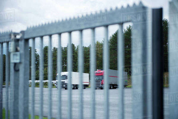 Trucks on road in front of metal gate - Stock Photo - Dissolve