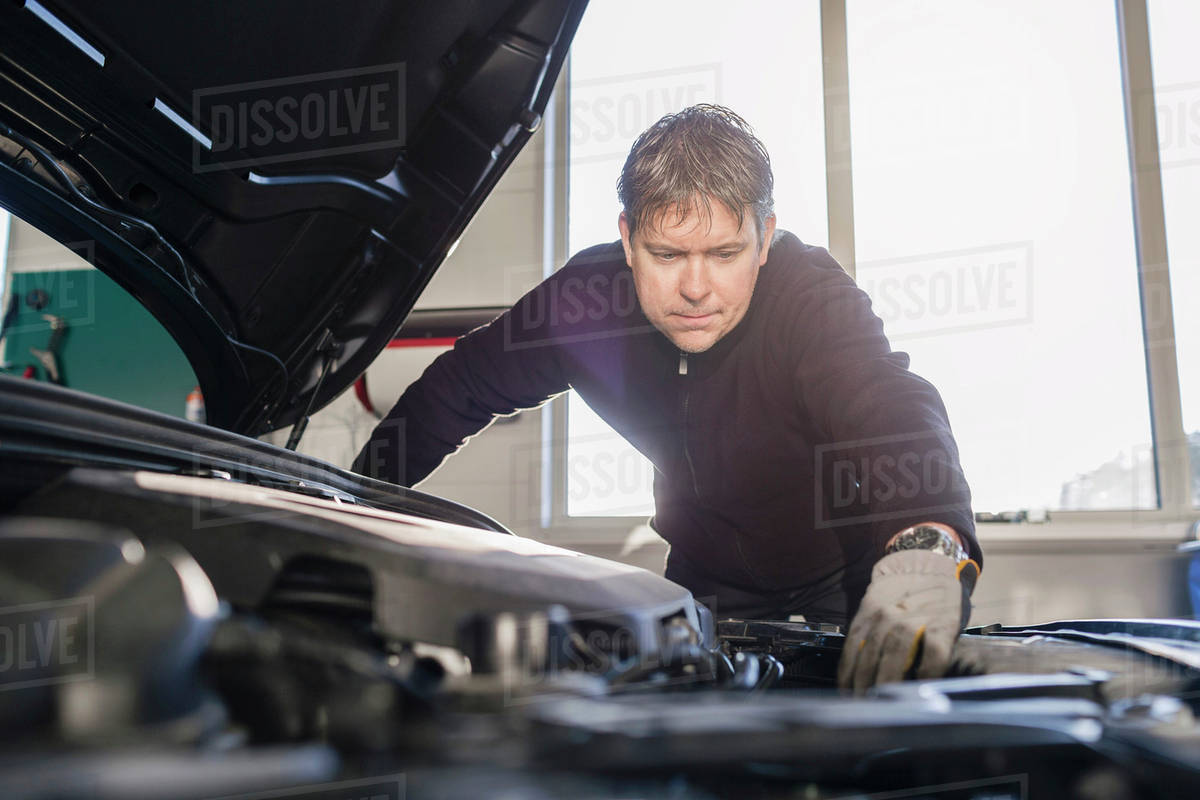 Mechanic repairing car engine in auto repair shop - Stock Photo - Dissolve