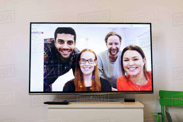 Happy business people on screen in video conference room at creative ...