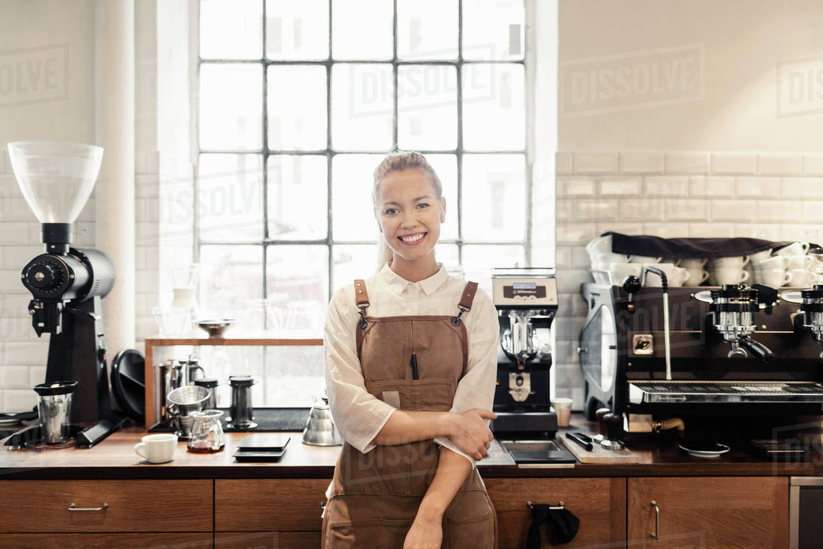 Portrait of happy female barista standing by counter in coffee shop ...