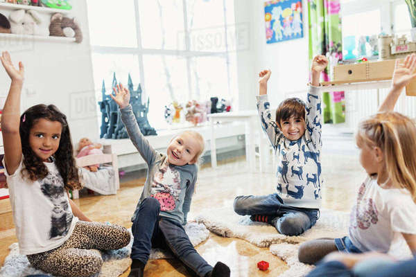 Happy children raising hands while sitting in preschool - Stock Photo ...