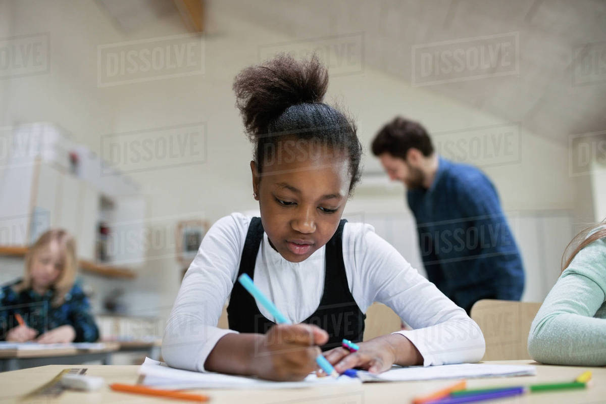 Concentrated student writing at desk in classroom - Royalty-free Stock ...
