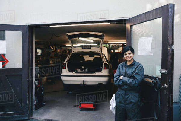 Portrait of confident female mechanic standing with arms crossed at ...