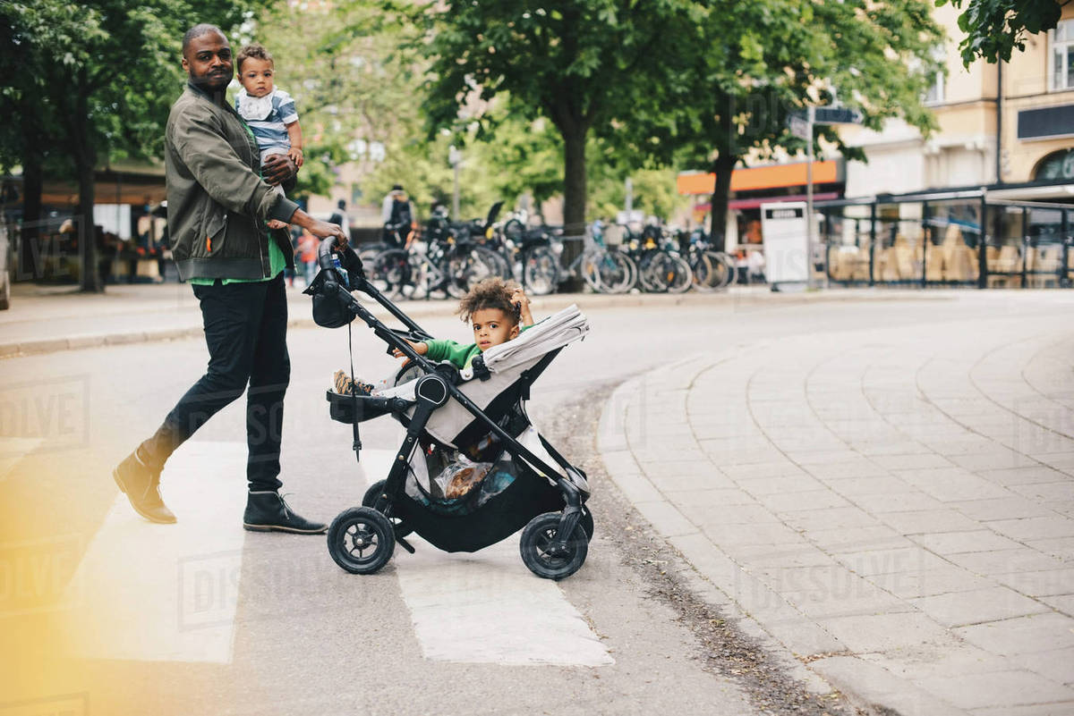 Father crossing road with son in city - Stock Photo - Dissolve