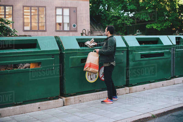 Full length of man throwing garbage in can - Stock Photo - Dissolve