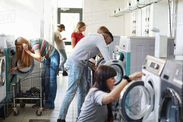 University students using washing machines at campus laundromat ...
