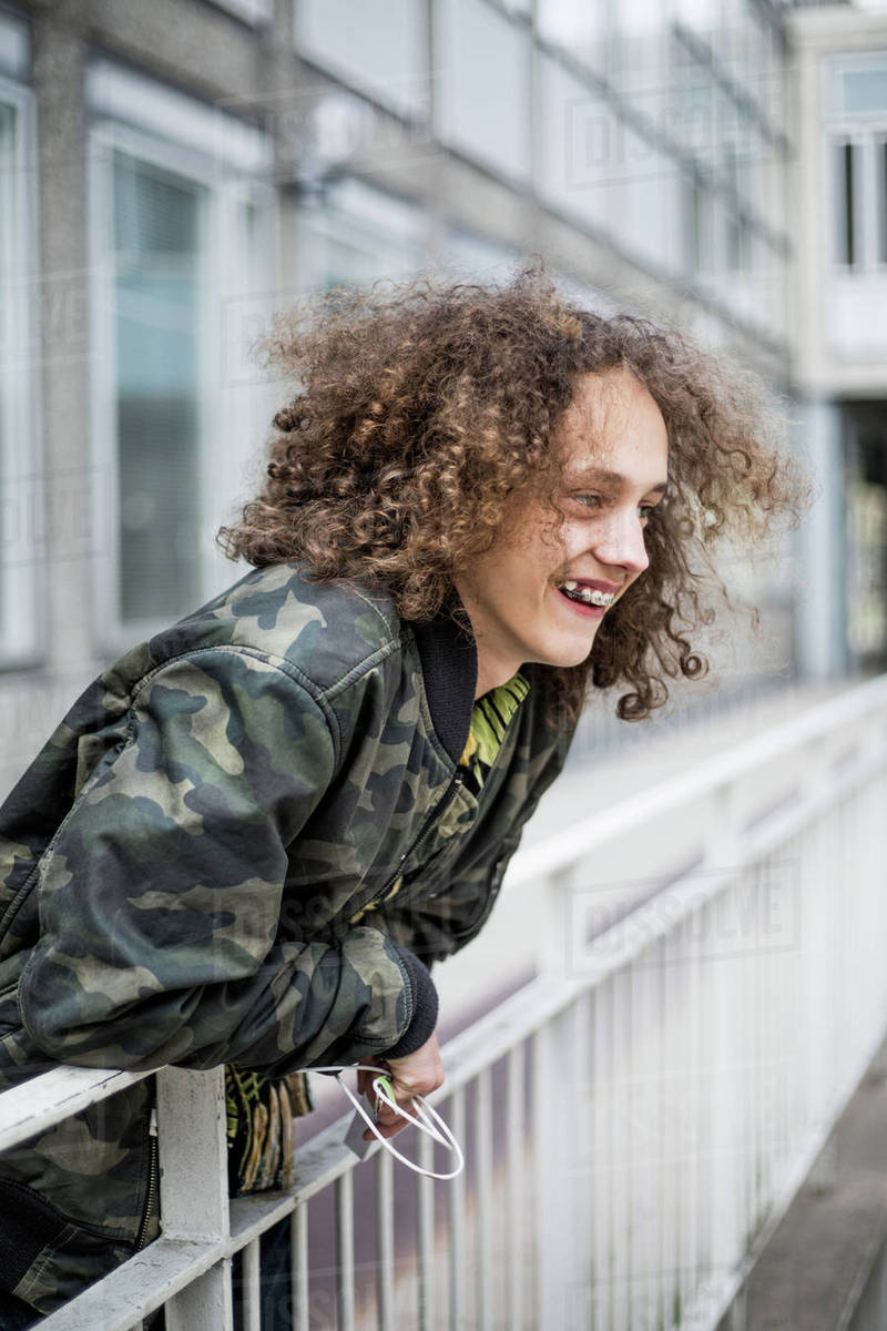 Smiling teenage boy leaning on railing in city - Royalty-free Stock ...