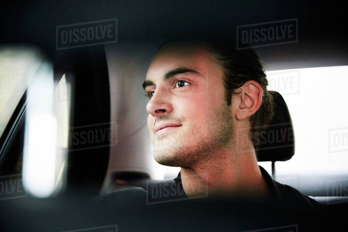 Close-up of smiling thoughtful man riding car - Stock Photo - Dissolve