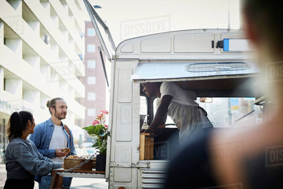 Salesman selling bread to male and female customers at food truck in ...