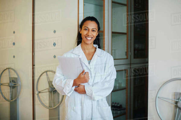Portrait of smiling young chemistry student wearing lab coat standing ...