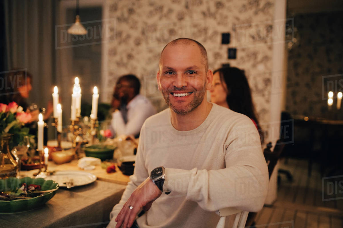Portrait of mature man with friends at dining table in dinner party ...