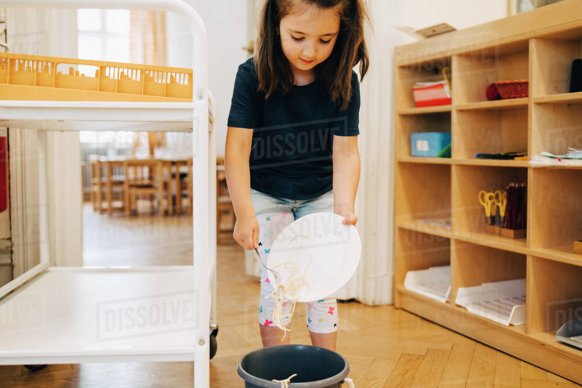 Girl throwing spaghetti in garbage can at kindergarten - Royalty-free ...