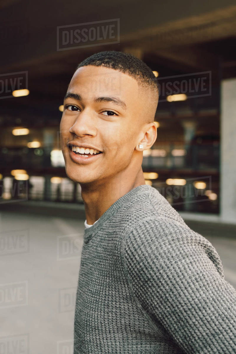 Side view portrait of smiling teenage boy standing in city - Royalty ...