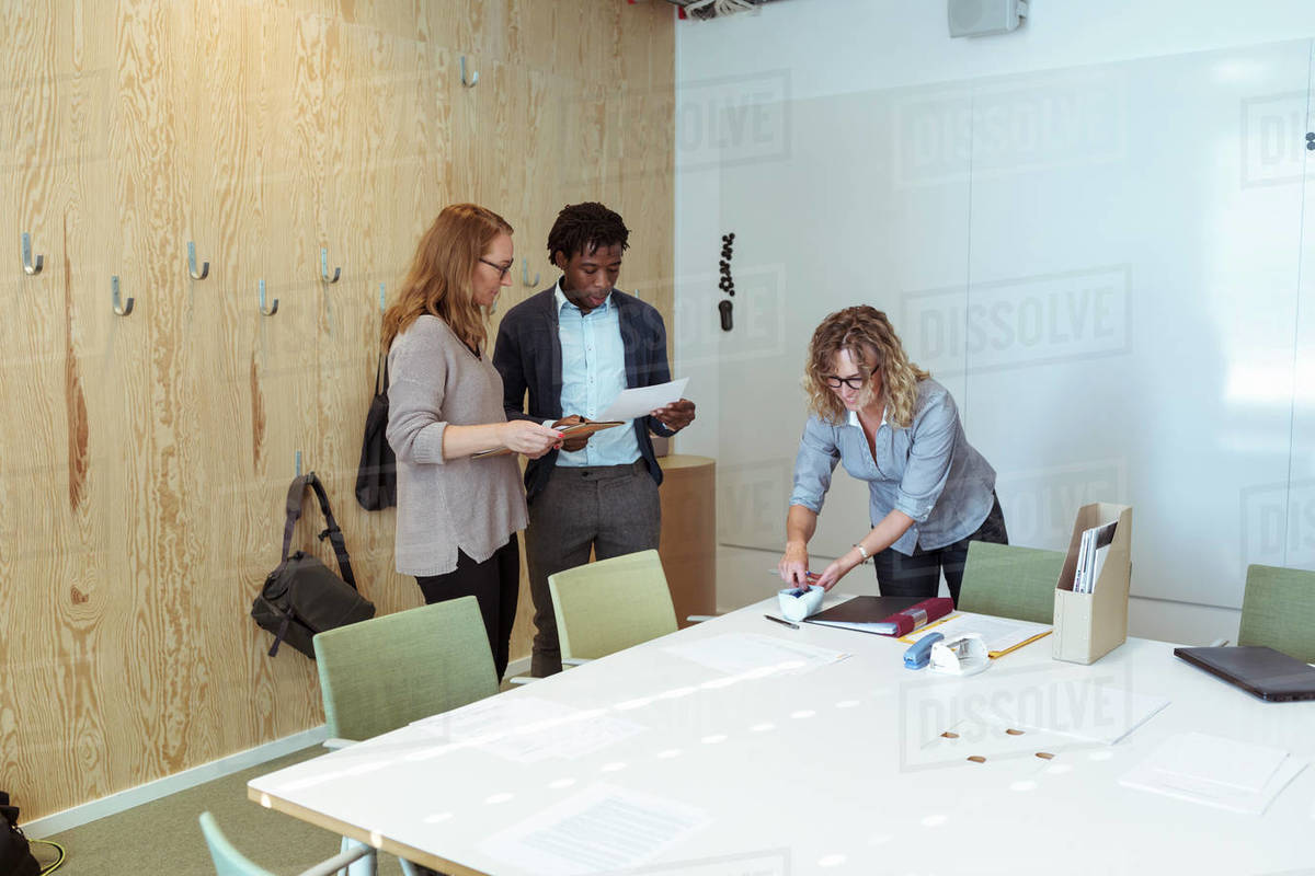 Male and female professionals working in board room at office - Royalty ...