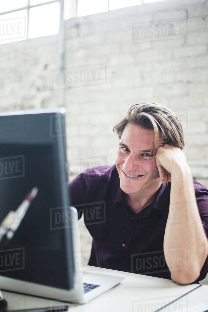 Portrait of smiling young male programmer coding at desk in office ...