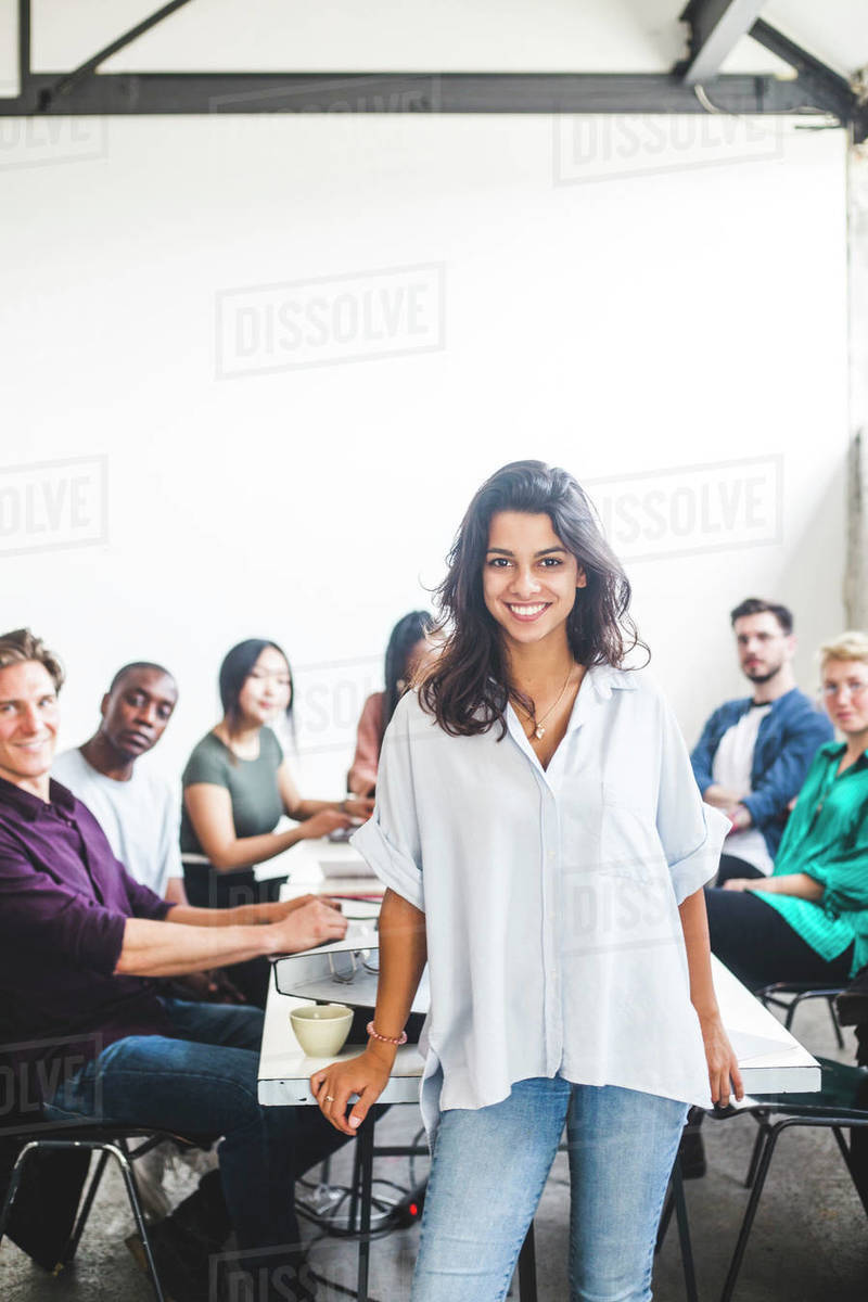Portrait of confident female programmer smiling while colleagues ...